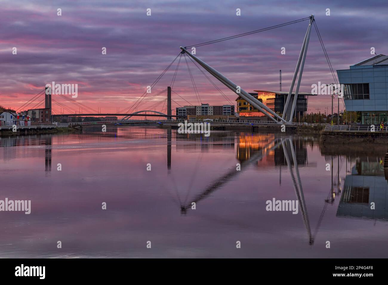 View of tidal river with footbridge and university building at sunrise ...