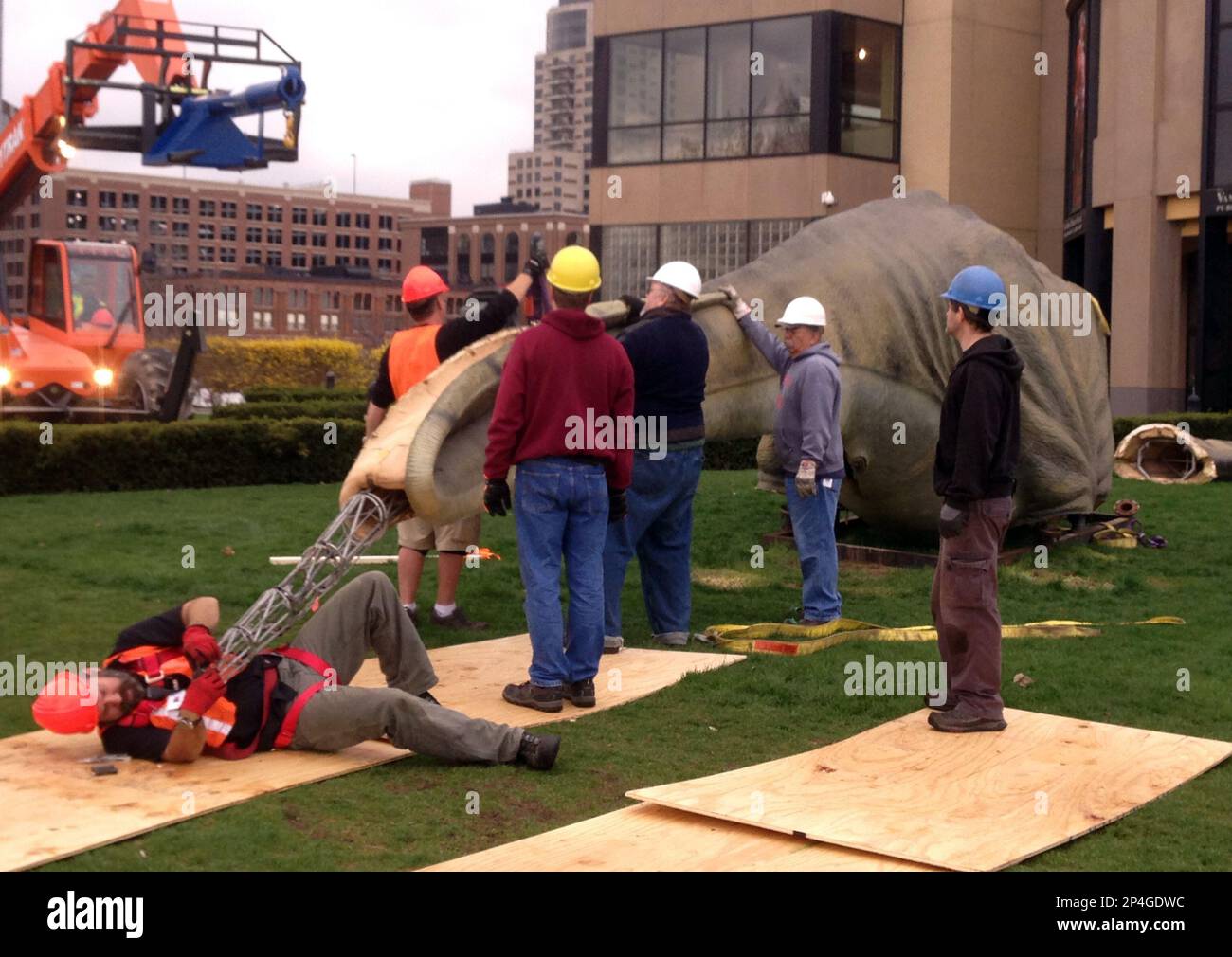 Construction workers take down a dinosaur in front of the Grand Rapids ...