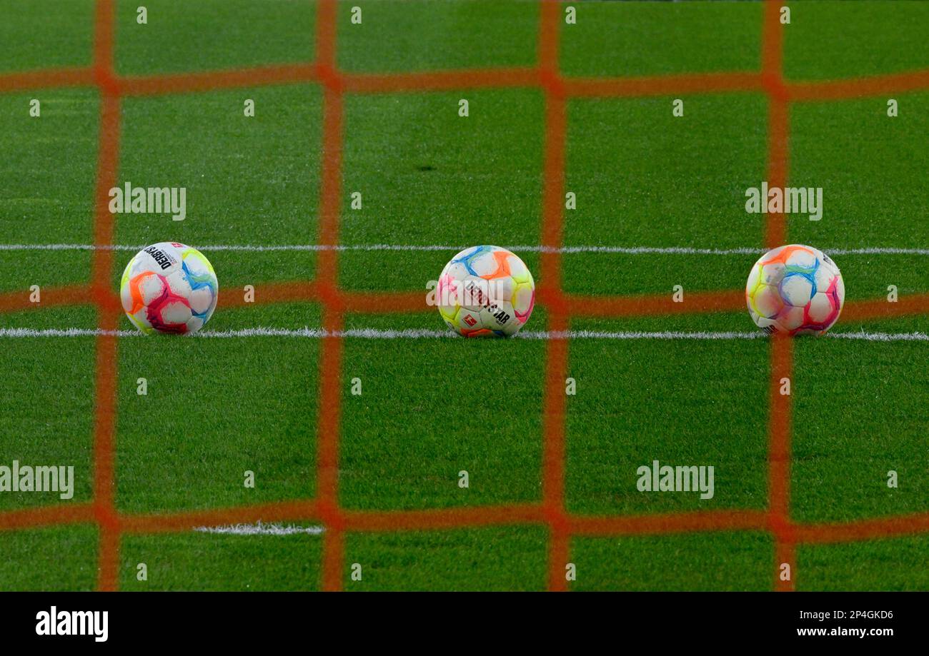 Three adidas Derbystar match balls lie on turf behind goal net ...