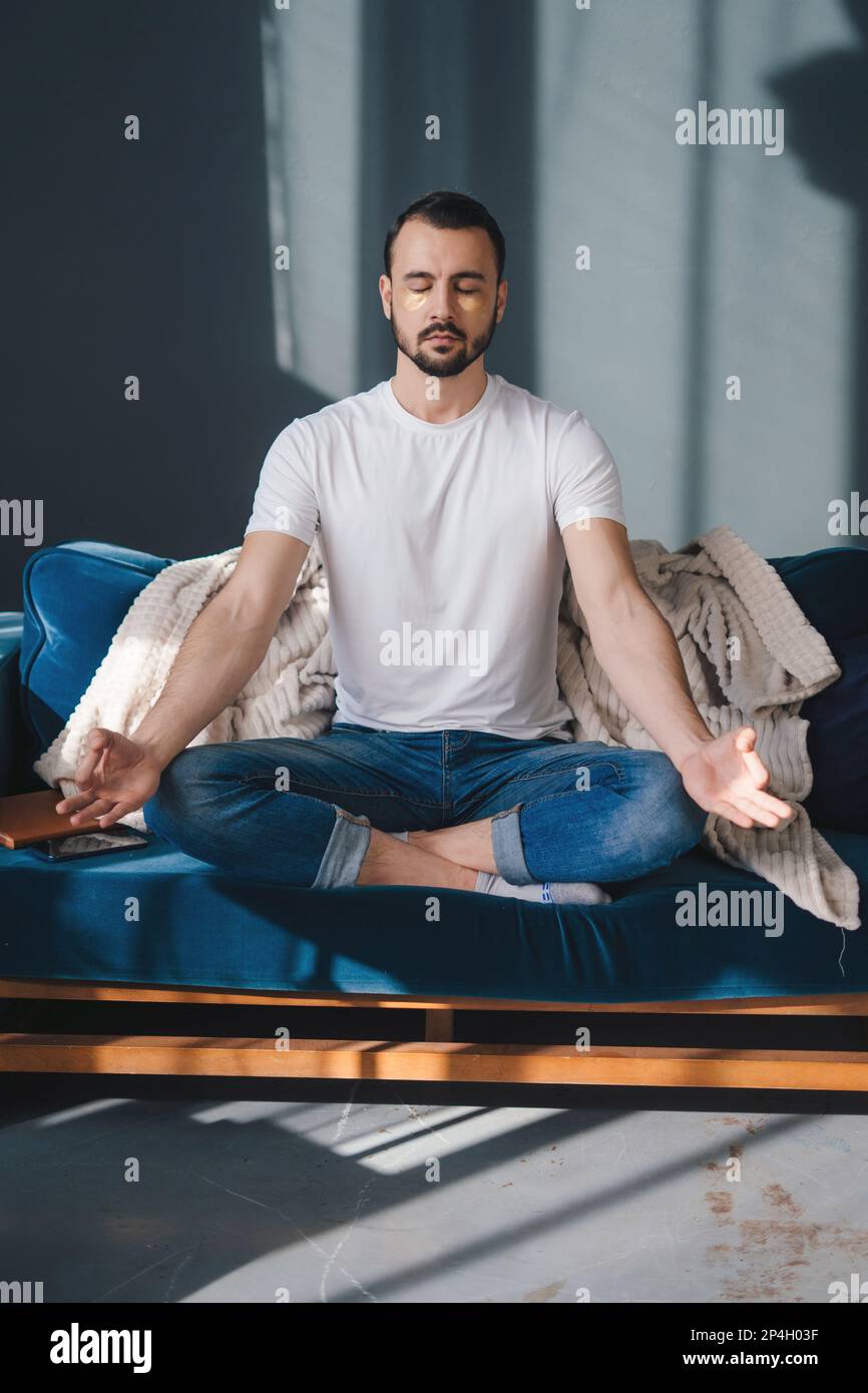 Peaceful millennial man relaxing with eyes closed on comfortable sofa ...