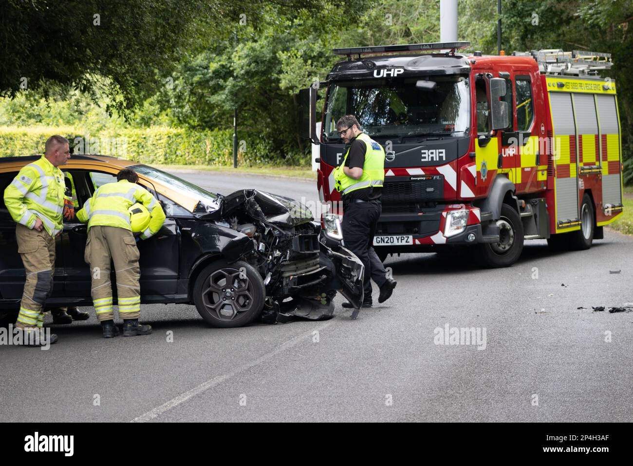 crashed car with fire fighters looking into window and fire appliance ...
