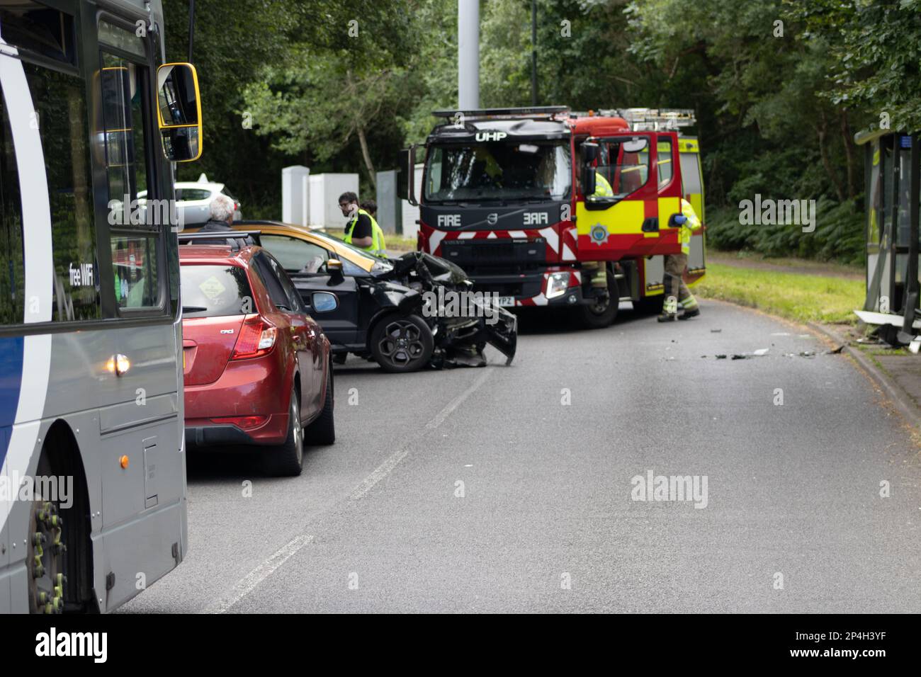crashed car blocking road. fire engins and men in attendance, debris in ...