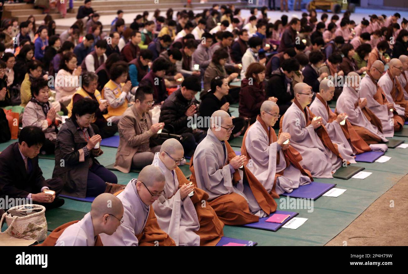 Buddhists and monks pray during a service to wish for safe return of ...