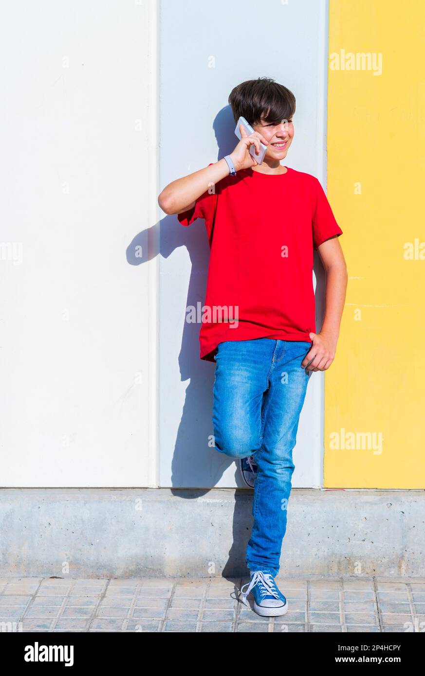 Young boy standing against a wall while talking by mobile phone Stock ...