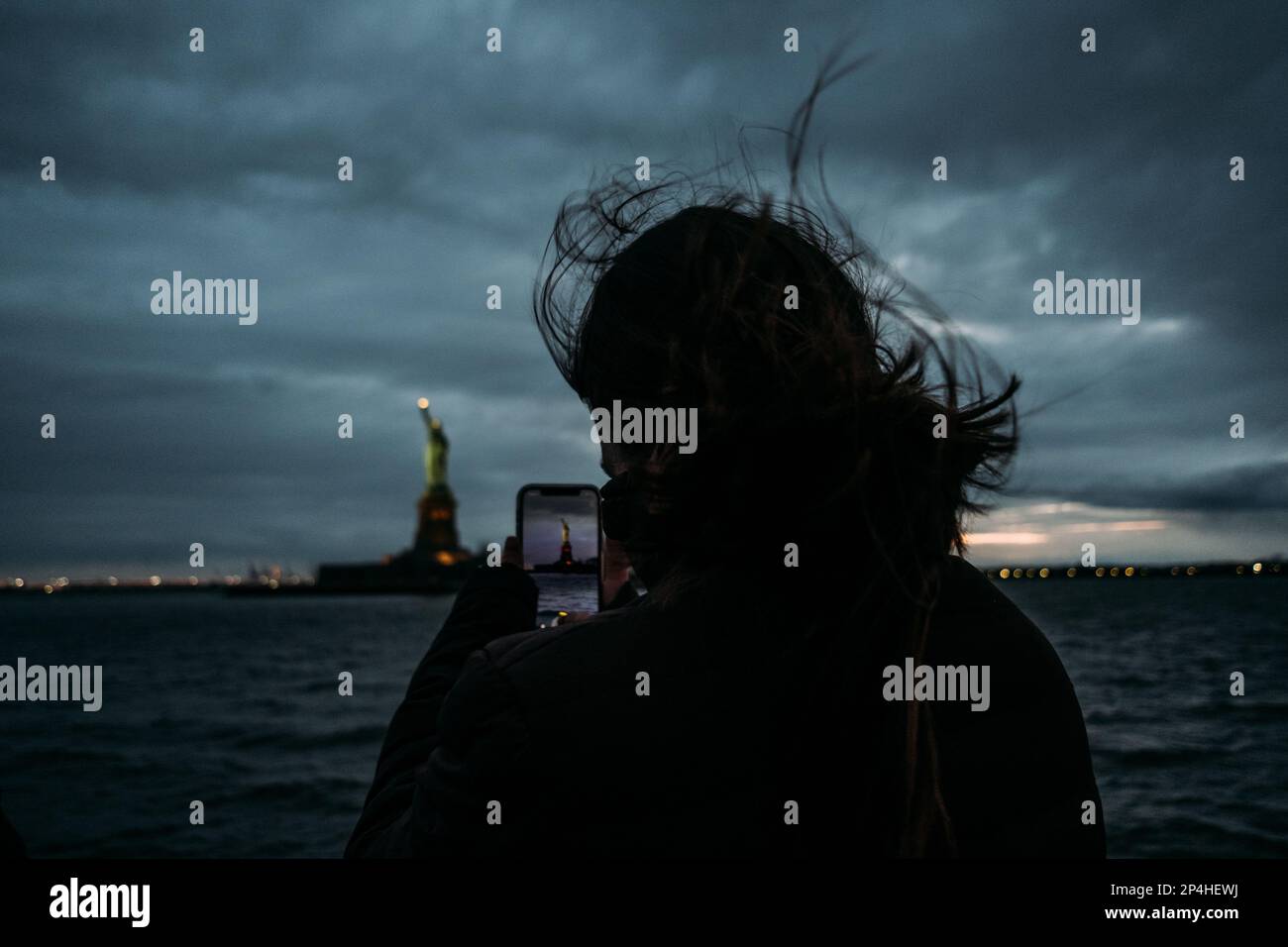 Woman taking a photo of Statue of Liberty on mobile phone Stock Photo ...