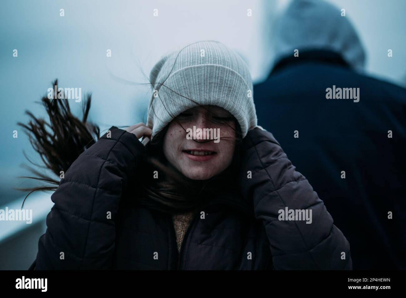 Teen girl holding on to hat on a cold windy day Stock Photo - Alamy