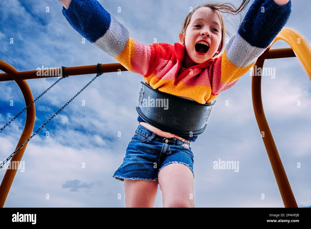 Young girl playing on swings at a park Stock Photo - Alamy