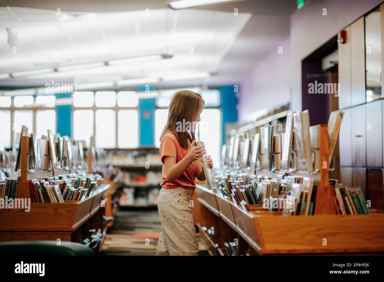 Tween looking at books at a library Stock Photo - Alamy