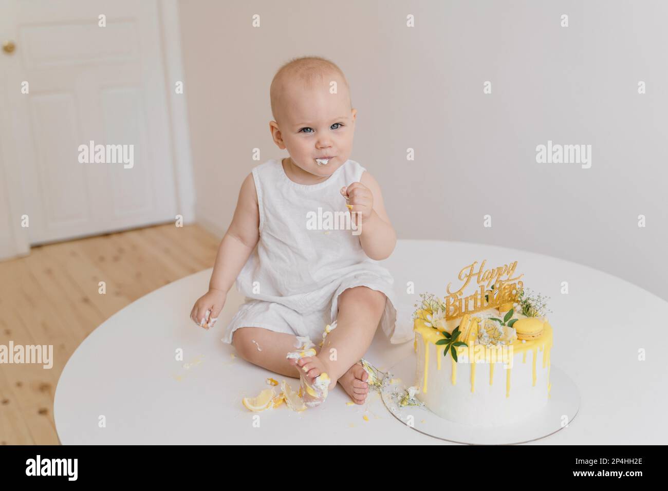 Baby girl eats birthday cake with her hands and legs Stock Photo - Alamy