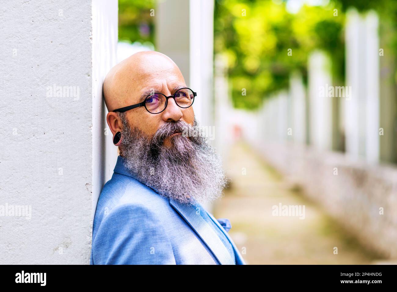 Hispanic, bald, bearded man leaning against a relaxed park column Stock ...