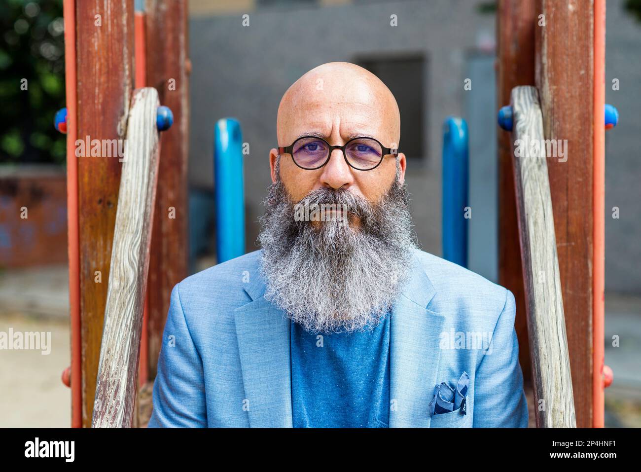 male, middle-aged, balding, bearded man sitting in a park relaxing ...