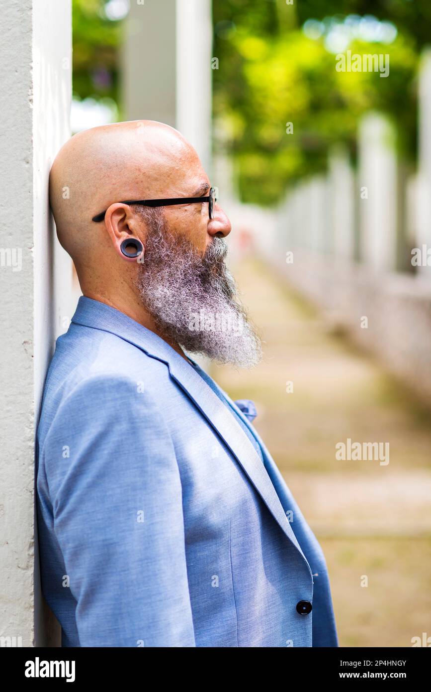 Hispanic, bald, bearded man leaning against a relaxed park column Stock ...