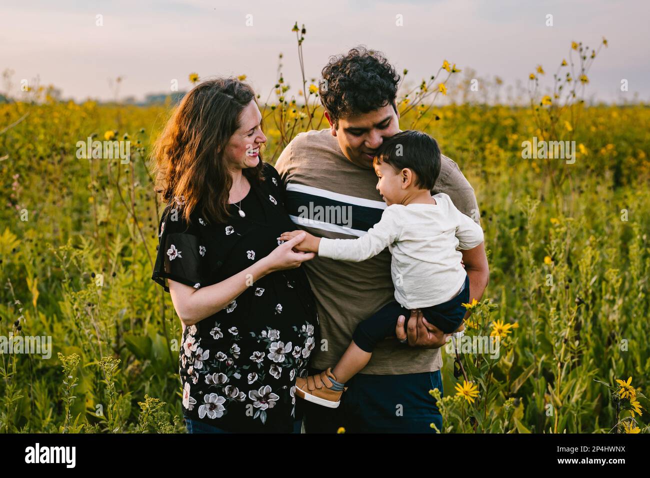 Love and togetherness of multiracial family in outdoor flower field ...