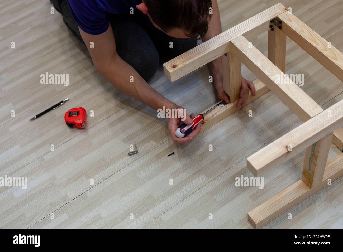 A man screwing metal corner to a wooden chair with a screwdriver Stock ...
