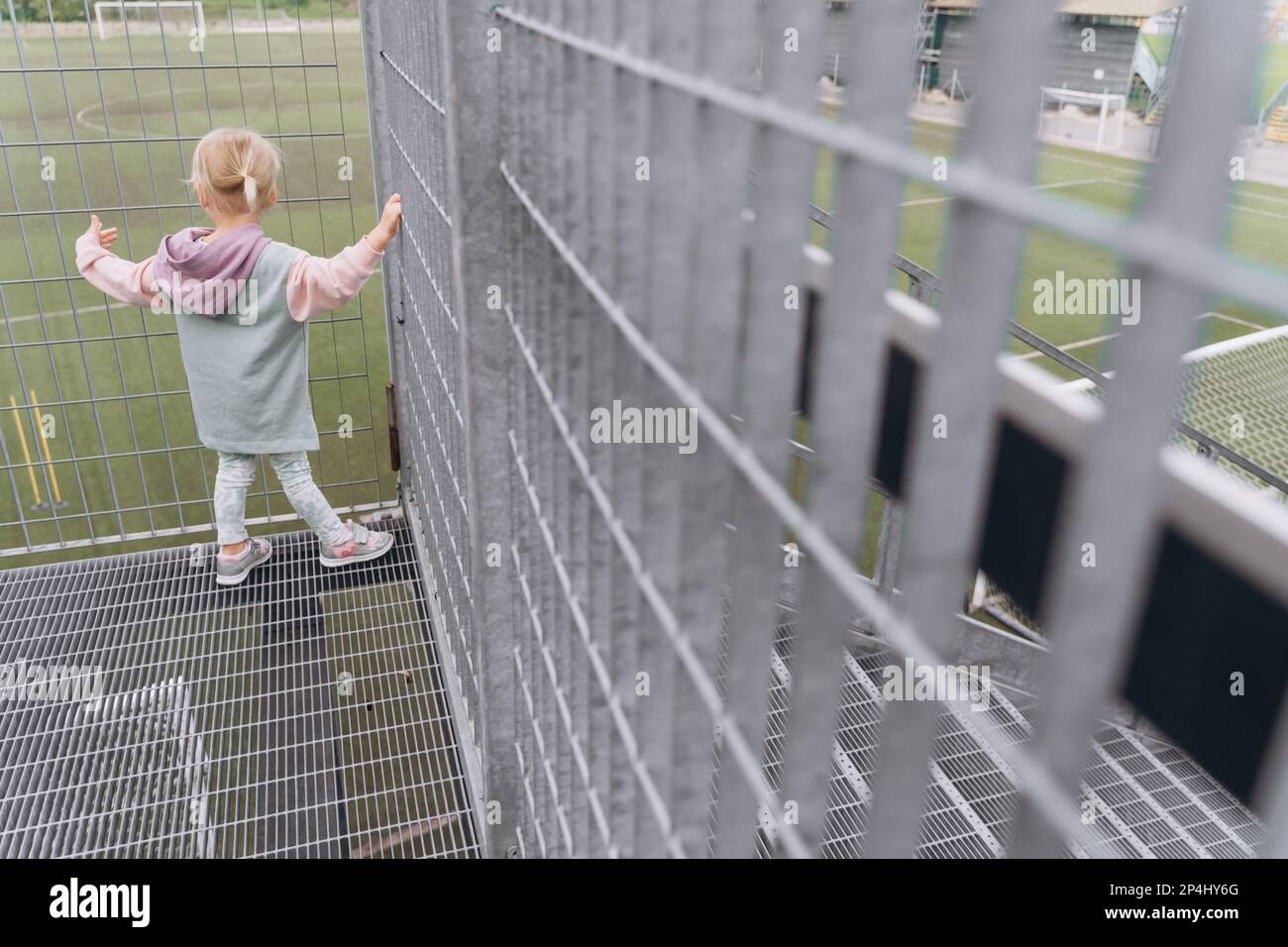 Dad and baby girl look through the bars at an empty football field ...