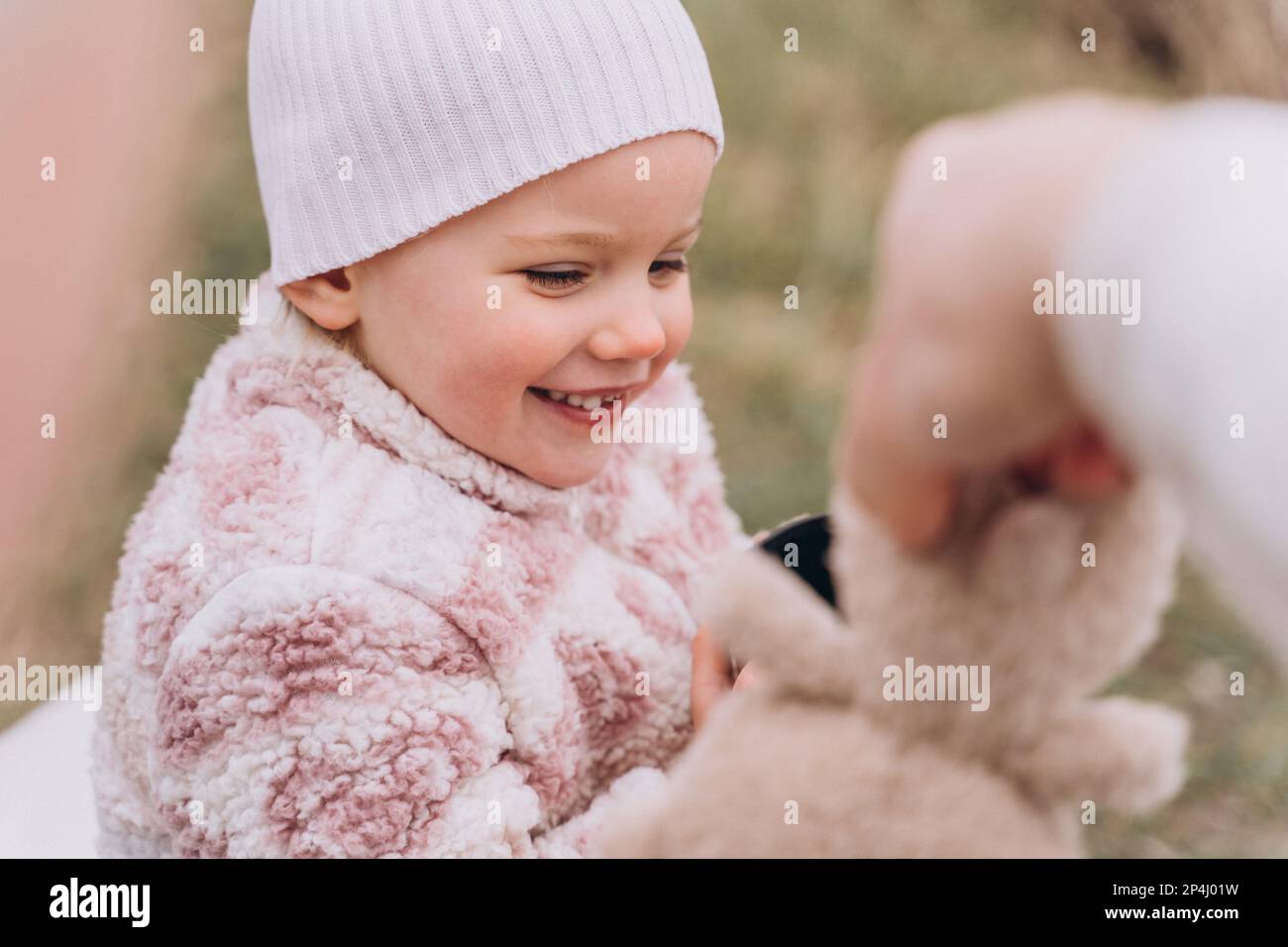 Toothless baby girl in the park laughs and drinks tea from thermos ...