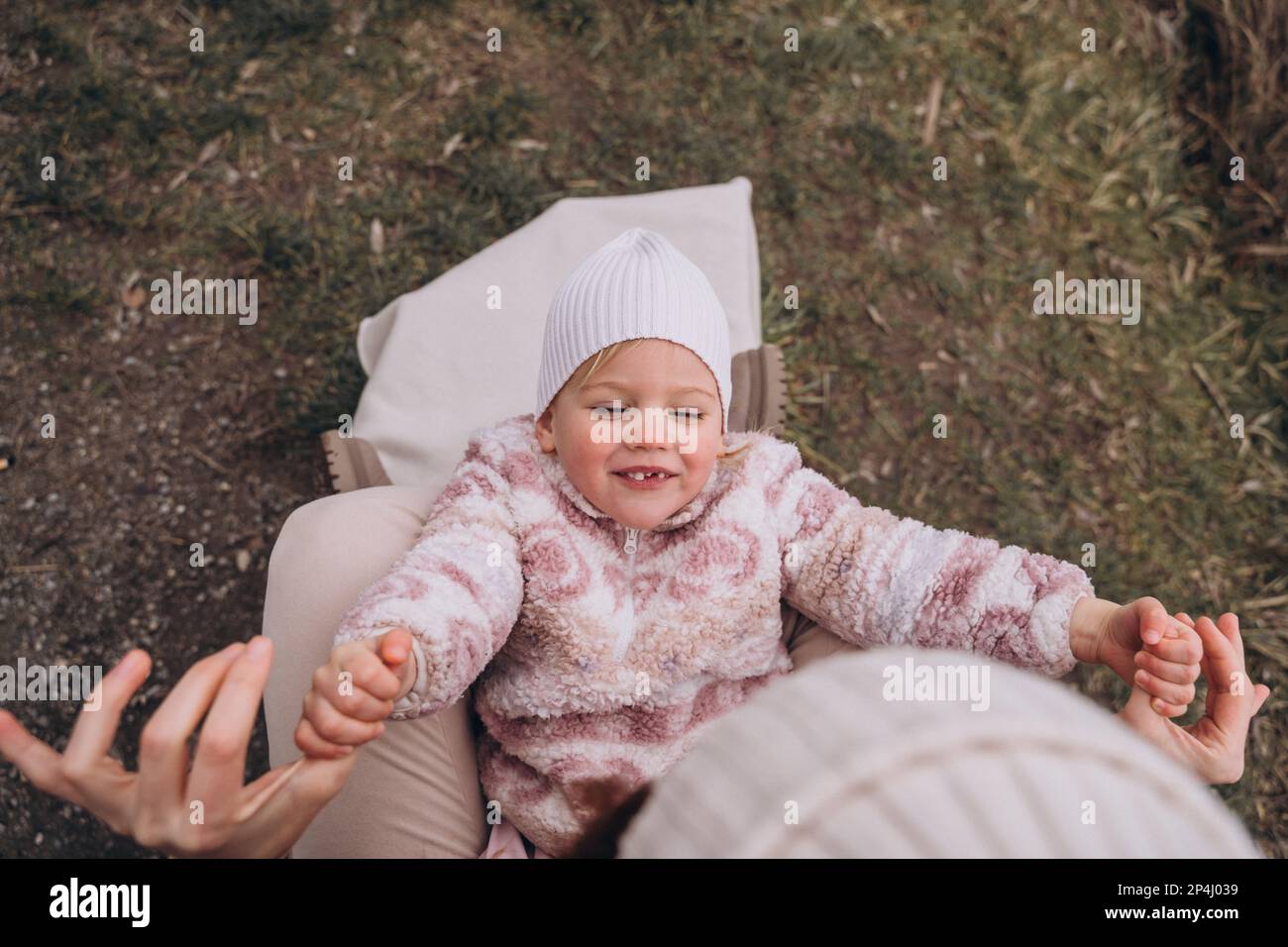 Toothless baby girl in her mother's hands outdoors in cold weather ...