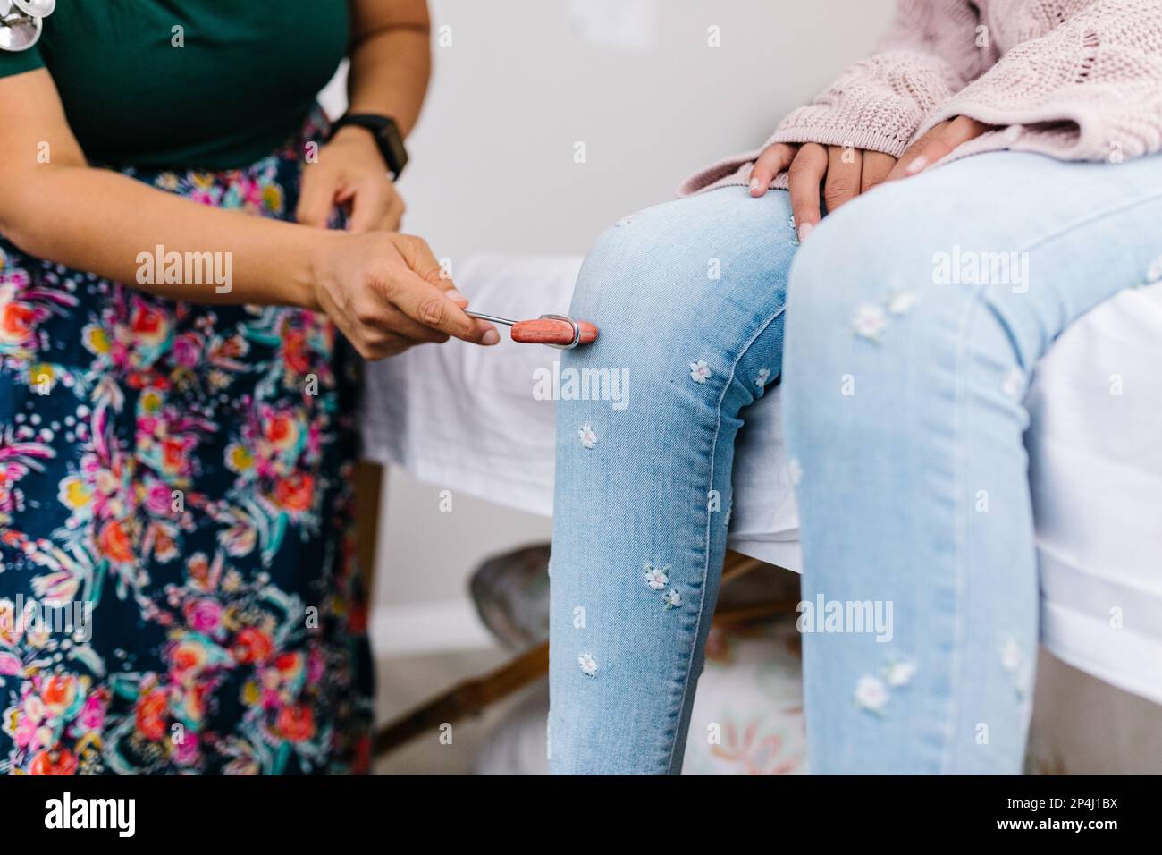 Doctor checking knee reflexes on a stylish biracial Child Stock Photo ...