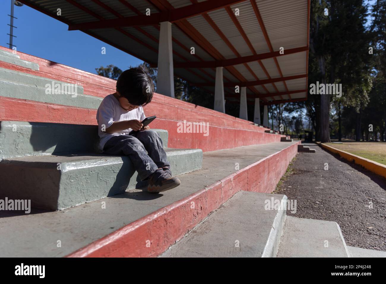 Mexican kid playing with Mobile Devices outdoors Stock Photo - Alamy