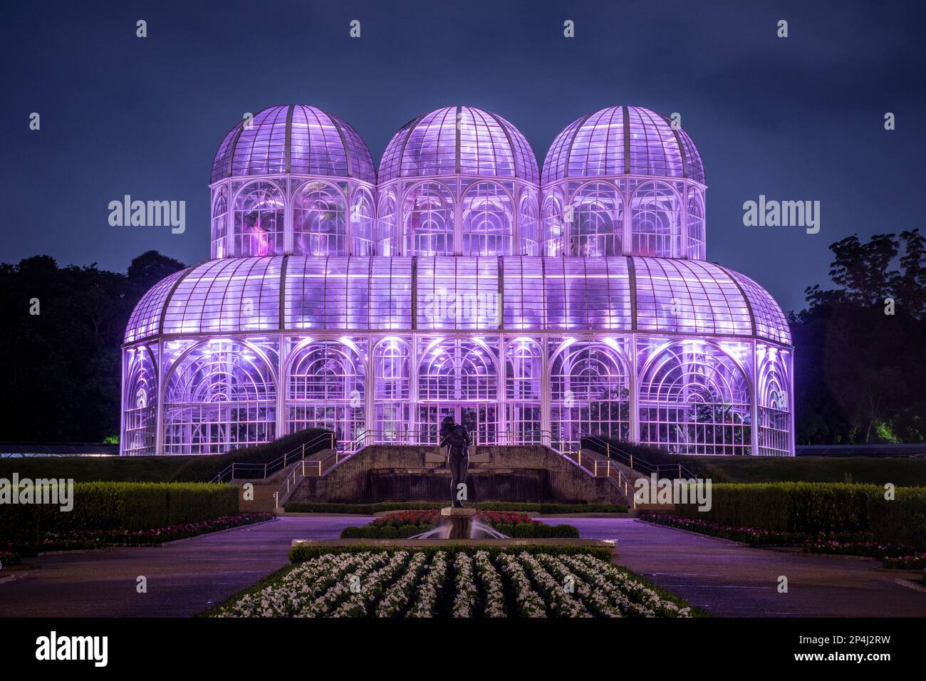 Beautiful view to glass greenhouse building shining purple at night ...