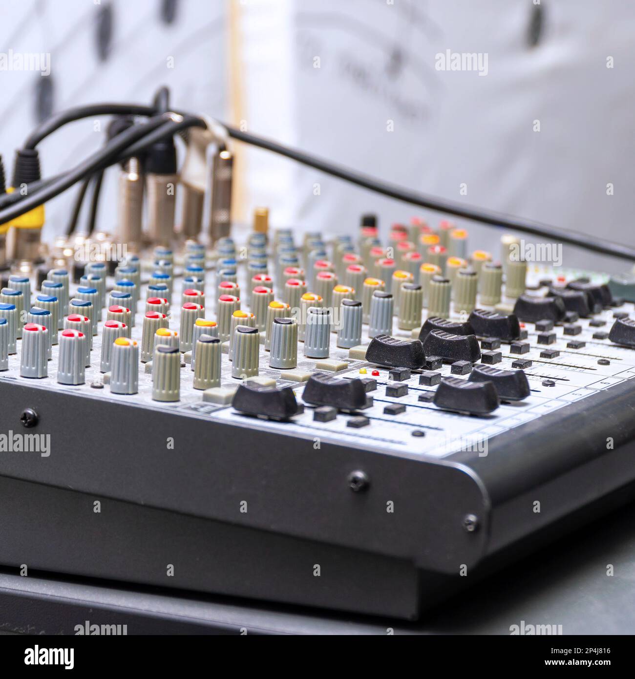 A small mixing console with cables with jacks inserted into console ...