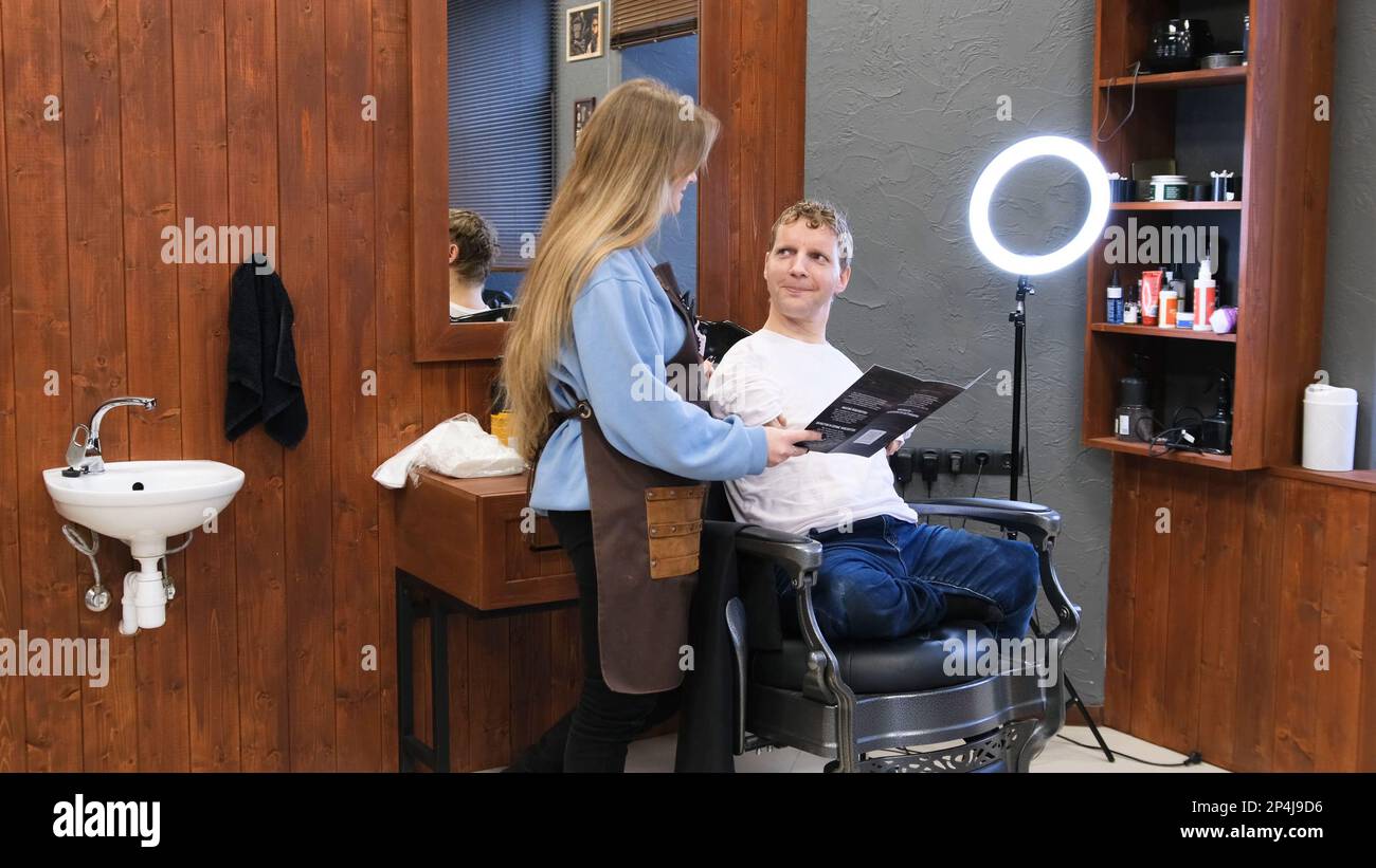 a young man with disabilities discusses a haircut with his master in a ...