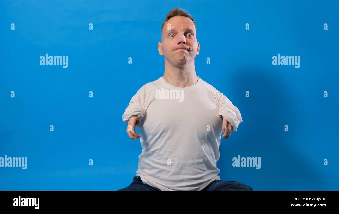 a young man with disabilities on a blue background is afraid and ...