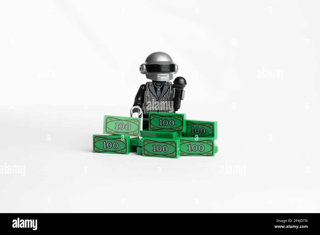 A Lego robot holding a microphone standing in front of a pile of lego ...