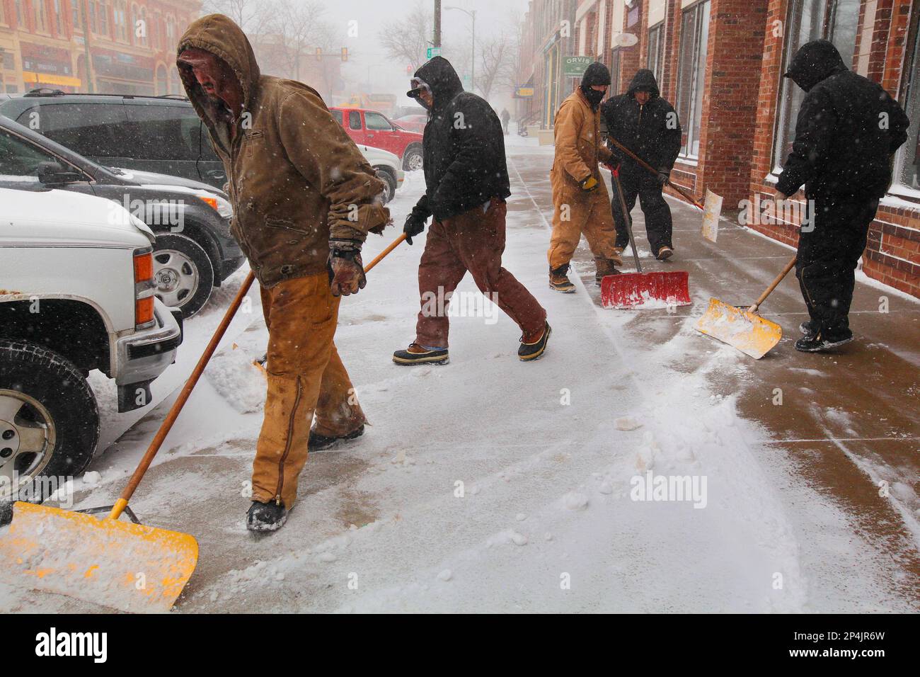 Employees with G.J. Holsworth & Sons shovel snow from the sidewalk in ...