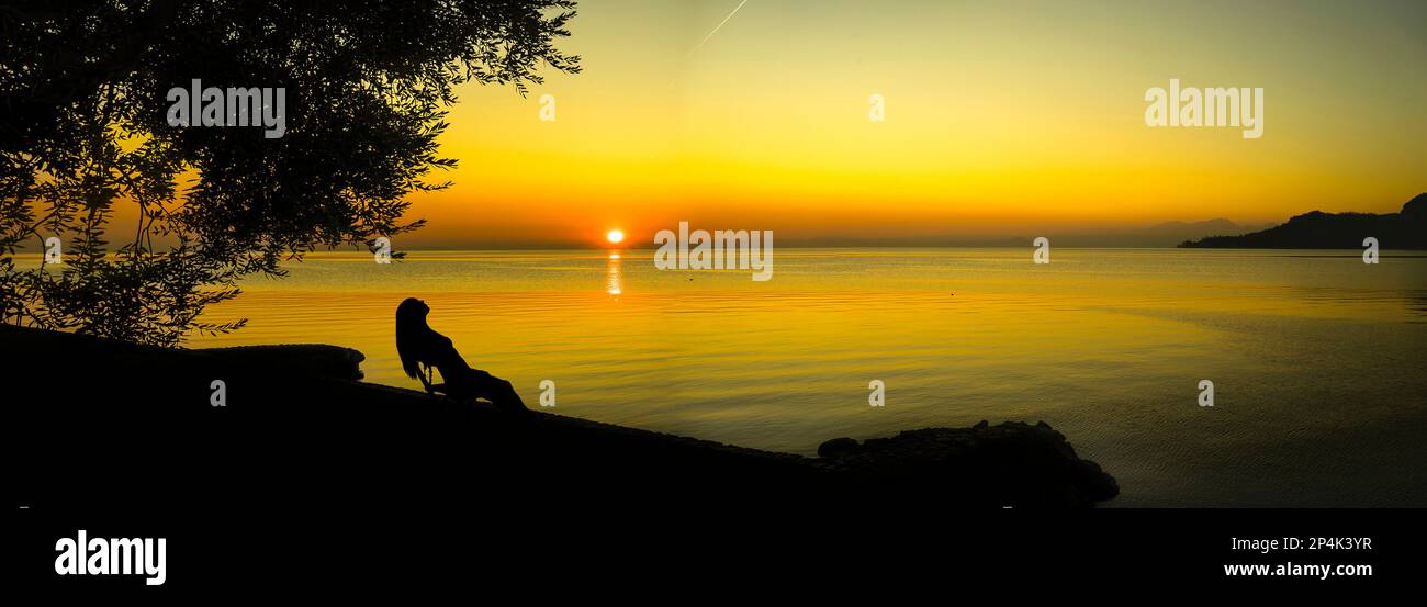 Woman sitting on shore sunset hi-res stock photography and images - Alamy