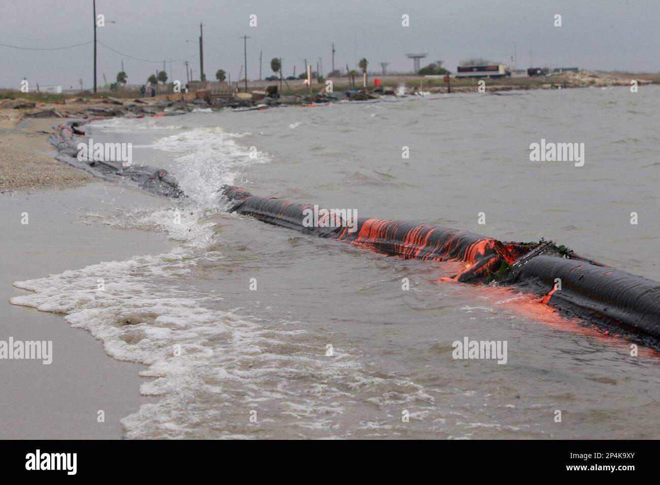 An oil containment boom is shown washed to shore on the beach area ...