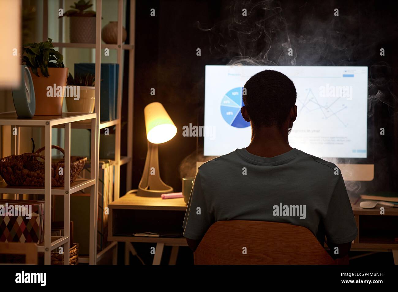 Rear view of young businessman smoking vape pen while sitting by ...