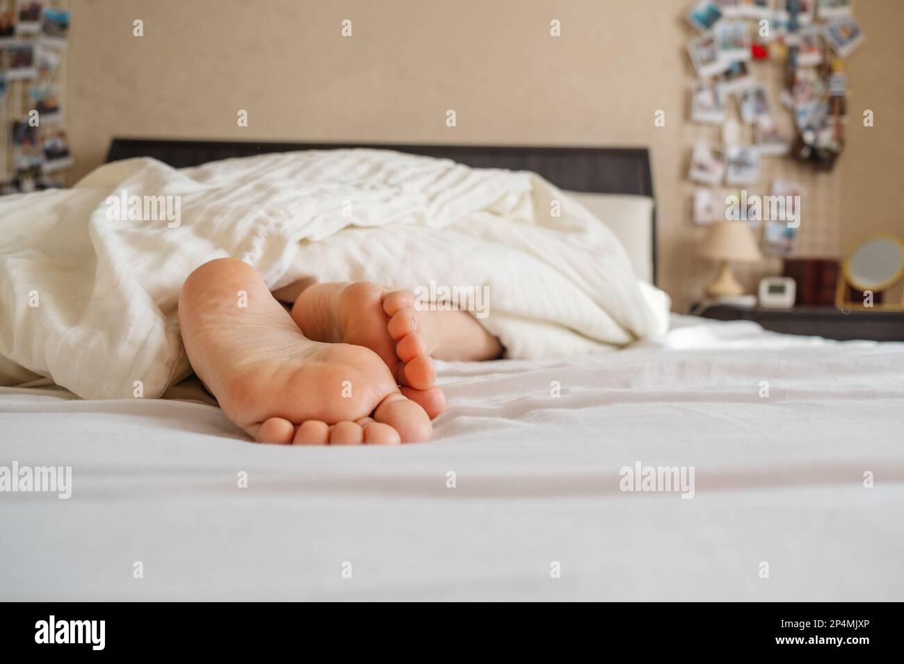 a woman's legs stick out from under the blankets as she sleeps Stock ...