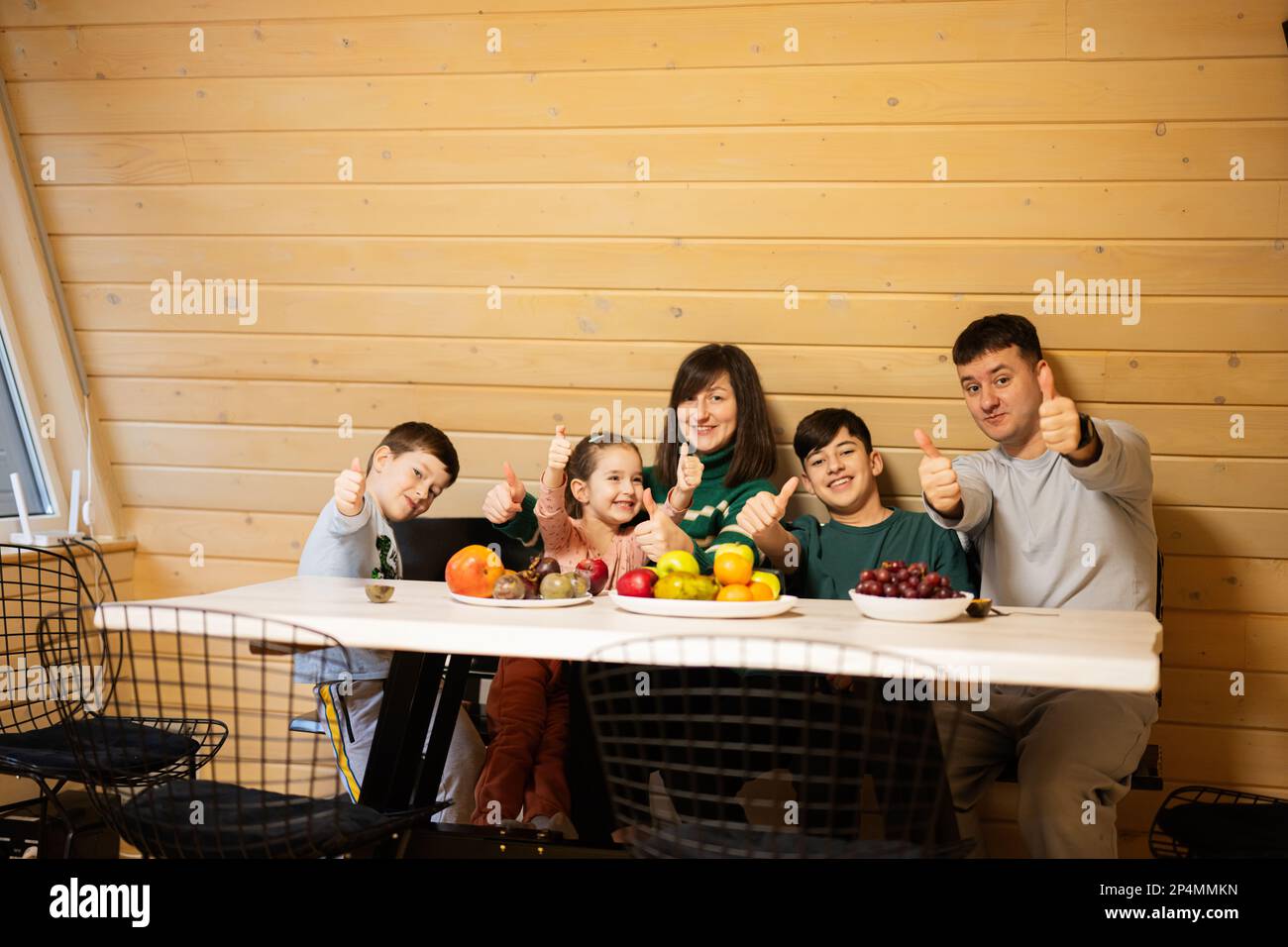Family with three kids eat fruits in wooden country house on weekend ...