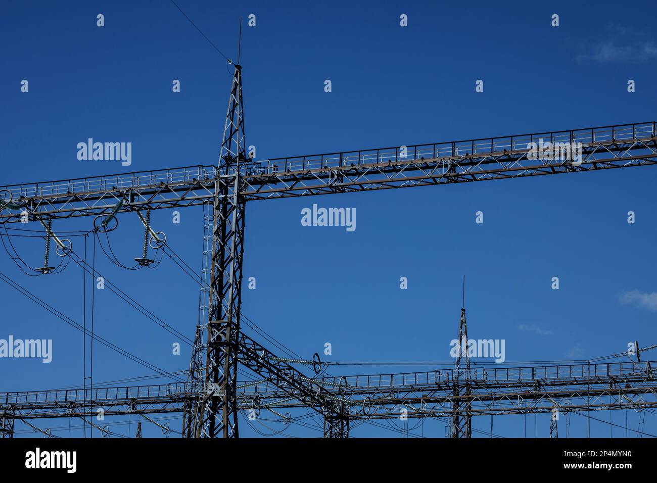 steel power pylon construction with high voltage cables against blue ...