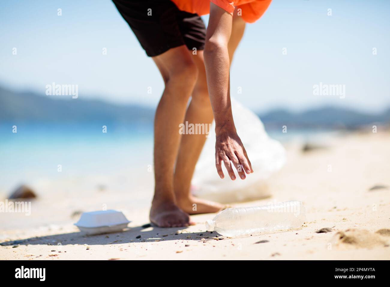 Plastic garbage. Sea and ocean pollution. Beach clean up. Young man ...