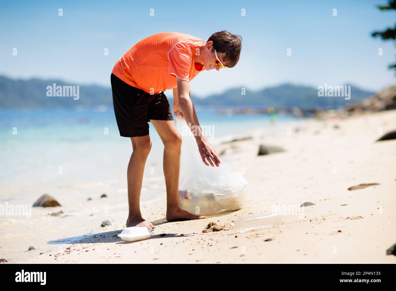 Plastic garbage. Sea and ocean pollution. Beach clean up. Young man ...