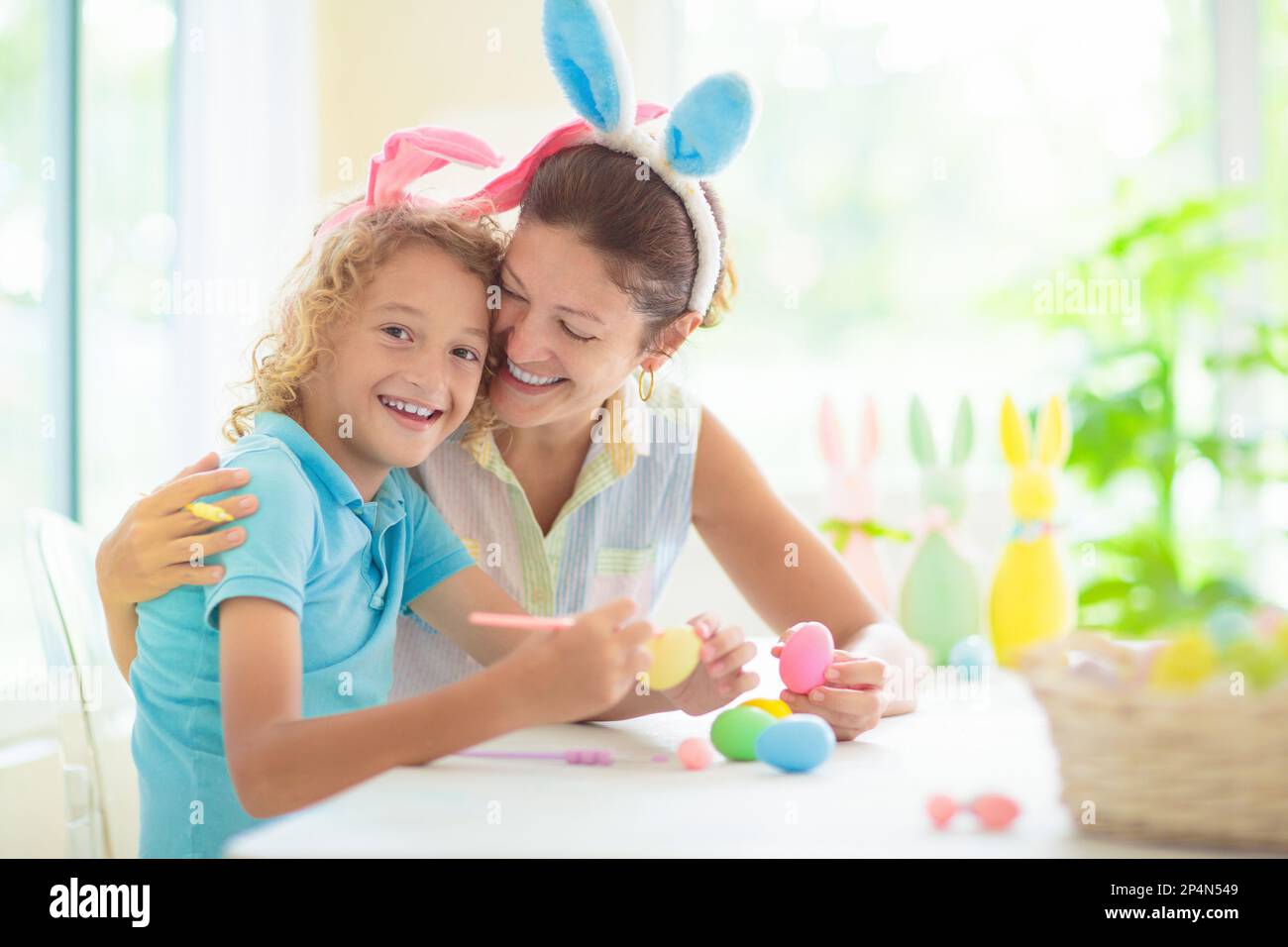 Mother and child color Easter eggs. Little boy with bunny ears and mom ...