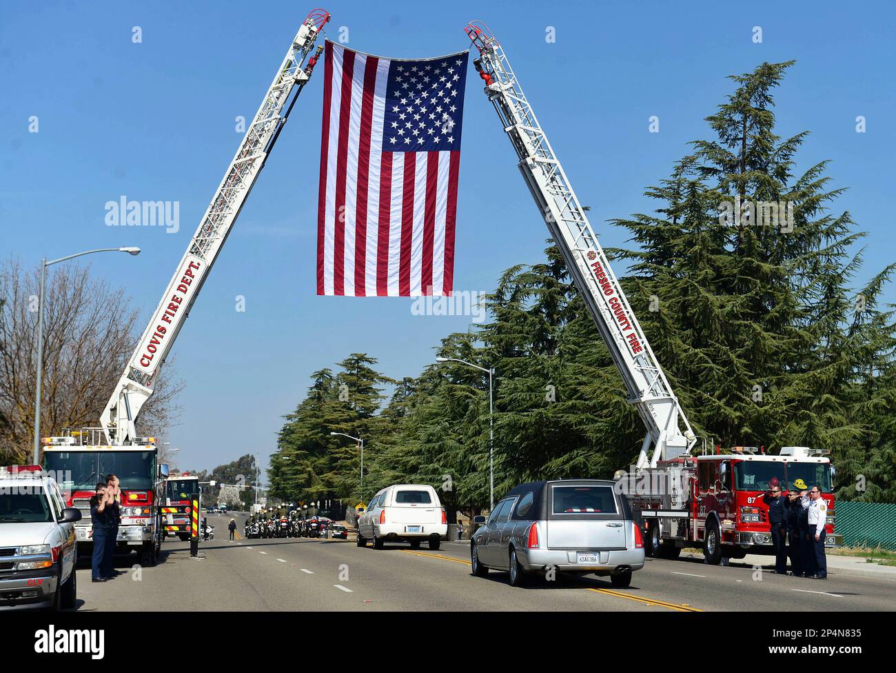 Members of the Fresno County and city of Clovis fire departments stand ...