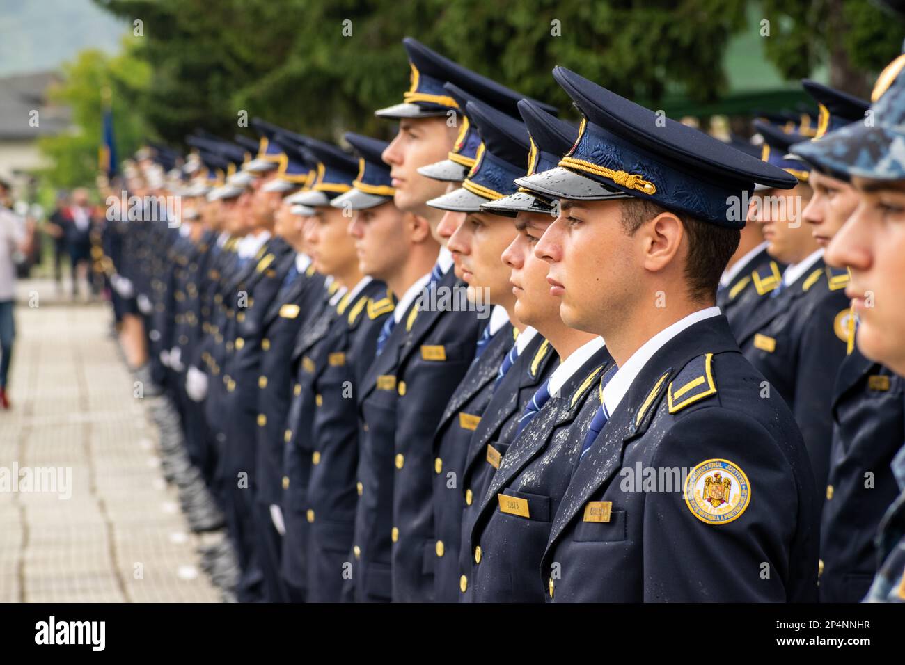 A group of soldiers wearing matching uniforms and hats stand in a neat ...