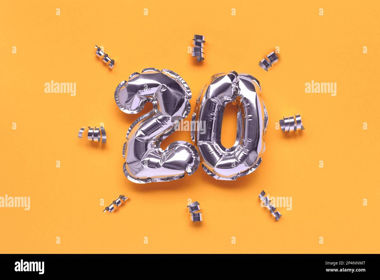 Number twenty silver balloons with ribbons confetti on a yellow ...
