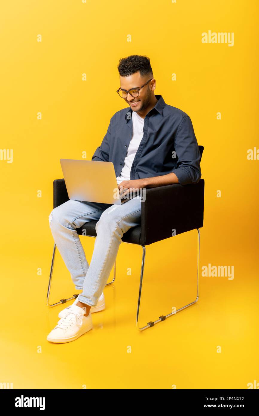 Happy Indian man looking at the laptop screen, typing information ...