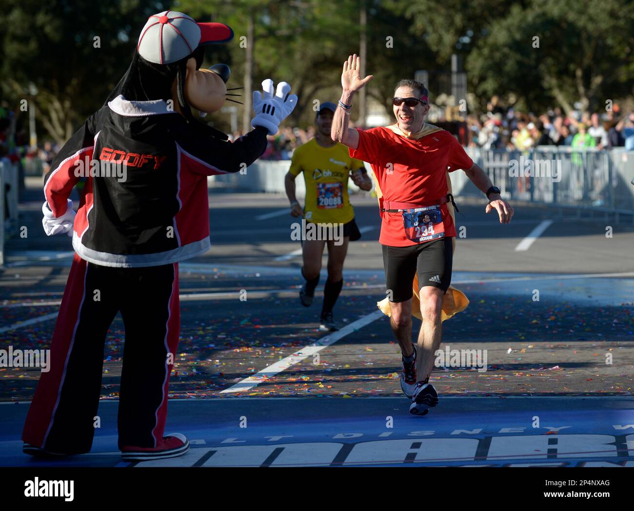 Runners are met by an actor dressed as Goofy, left, at the finish line ...