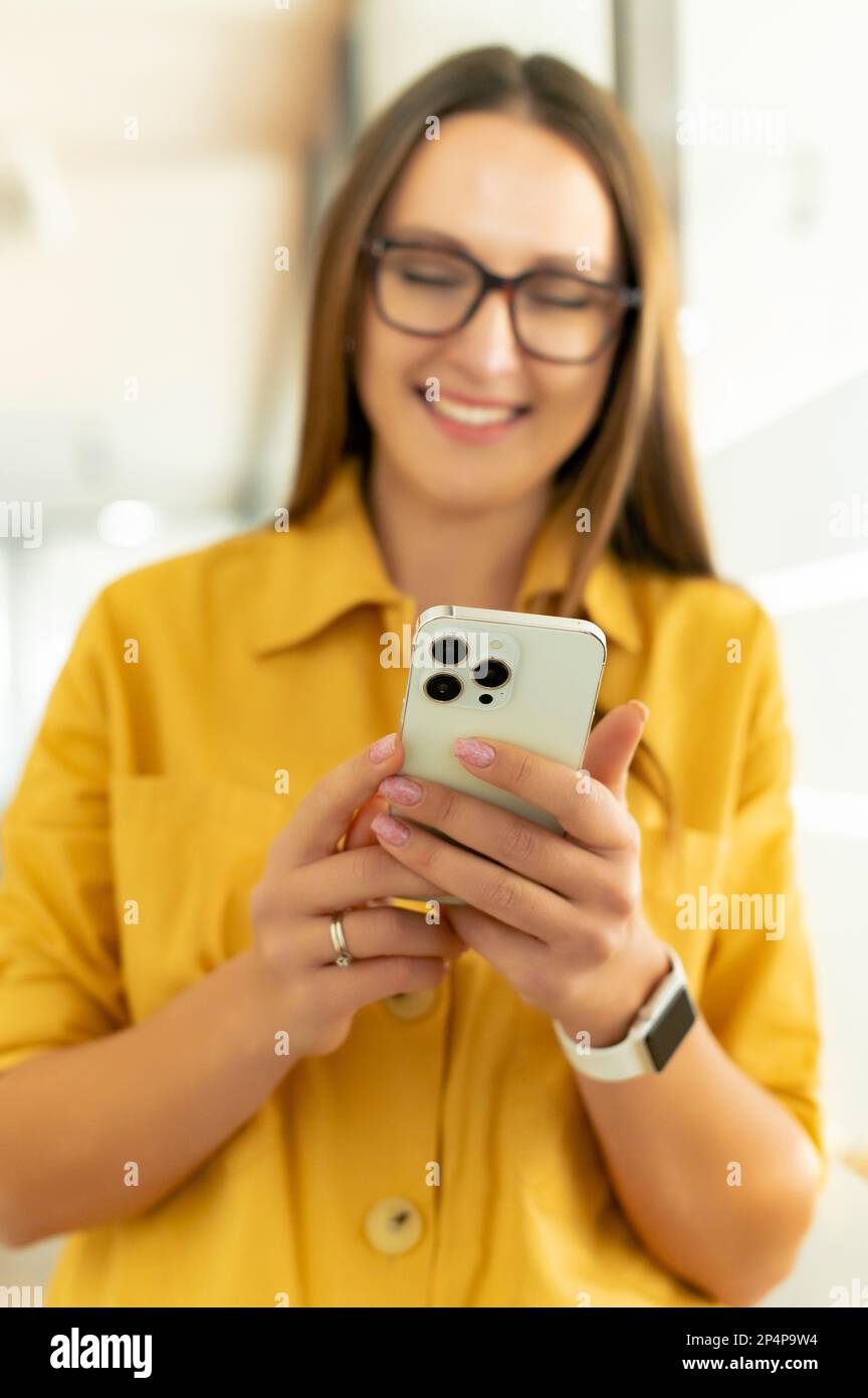 Vertical view of the laughing business lady holding smartphone and ...