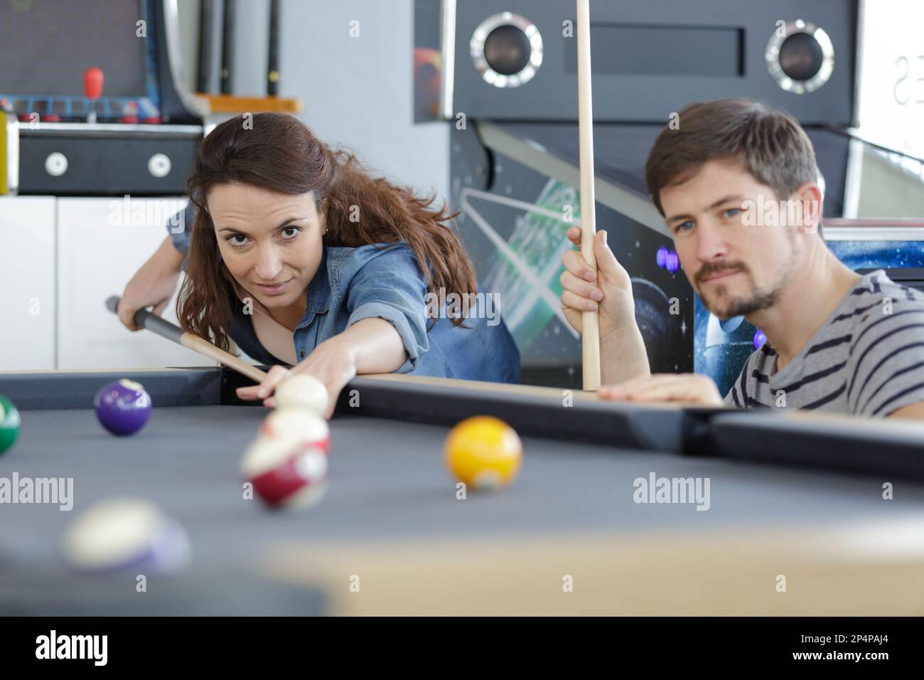 couple playing pool with woman taking aim Stock Photo - Alamy