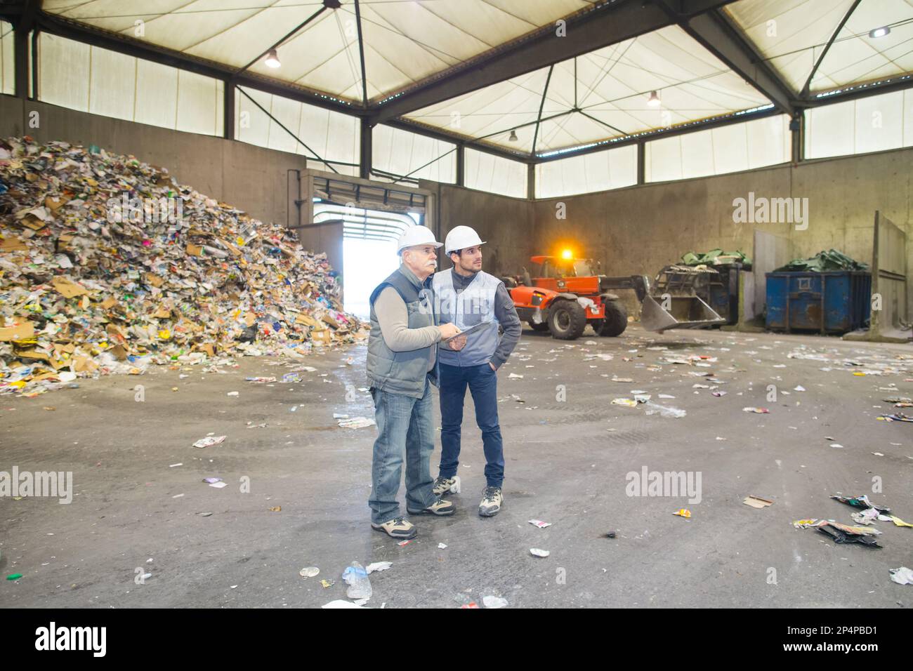 full length view of two men in recycling center Stock Photo - Alamy