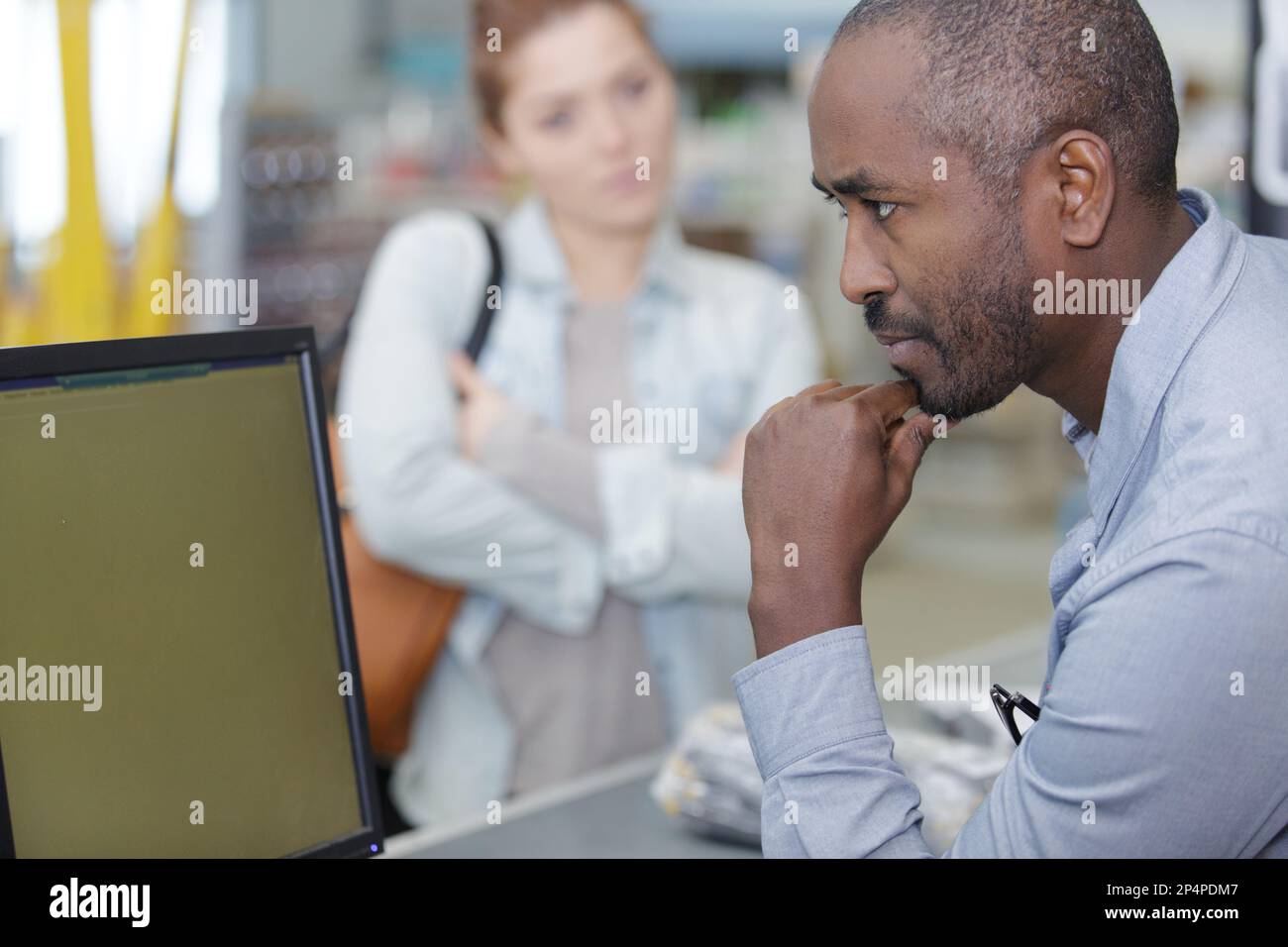 portrait of salesman using computer at cash counter in supermarket ...