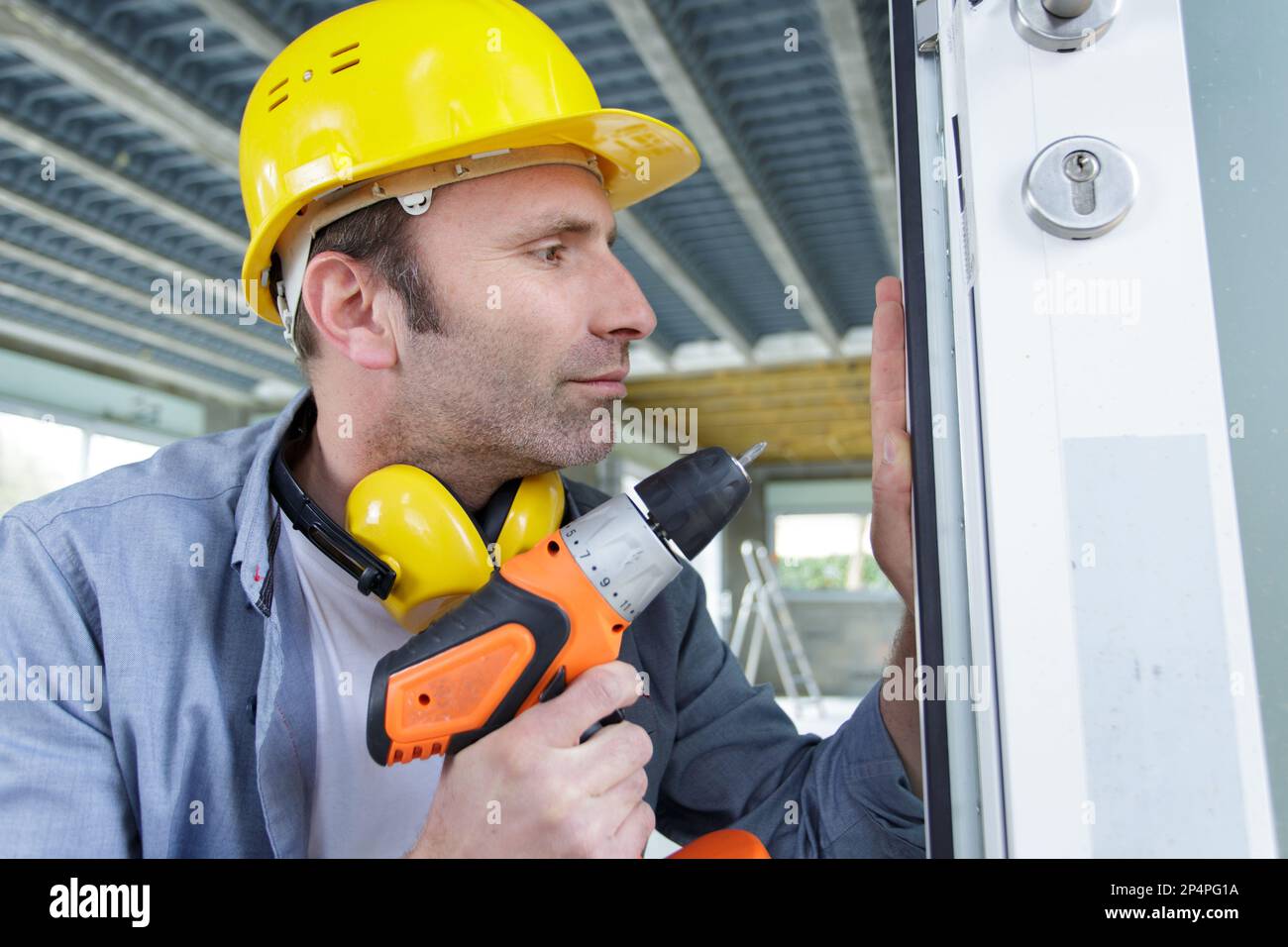 man drilling a hole in a window frame Stock Photo - Alamy