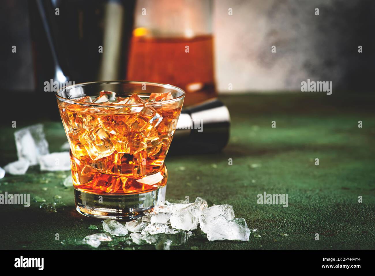 Godfather cocktail with scotch, amaretto liqueur and ice. Green bar ...