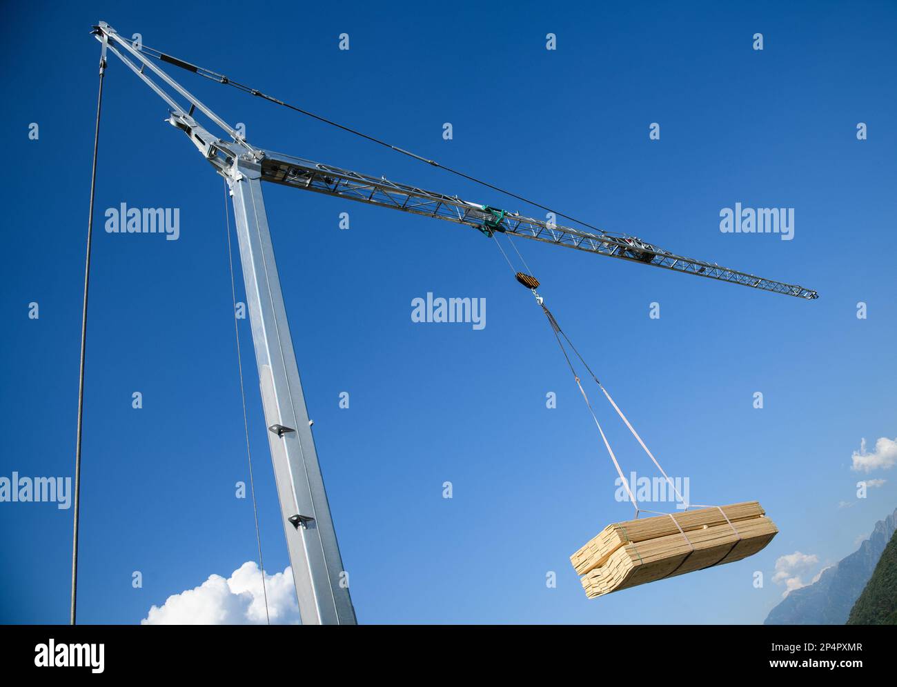 Construction crane with hanging load of wood plank on a blue sky Stock ...